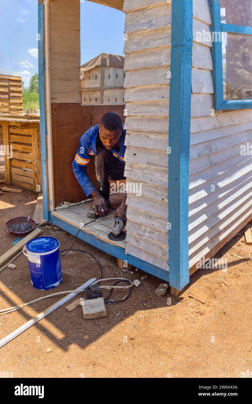 african american worker making a wendy house, wooden shed outdoors, he ...