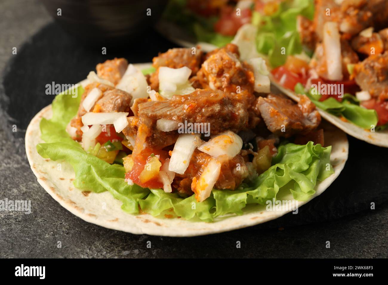 Delicious tacos with vegetables and meat on grey textured table ...