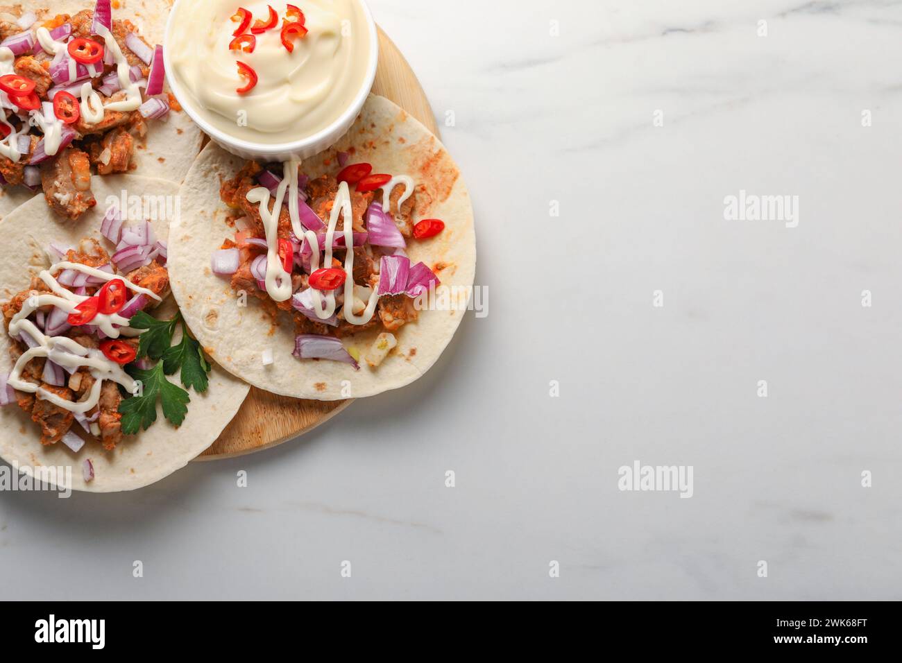 Delicious tacos with vegetables, meat and sauce on white marble table ...