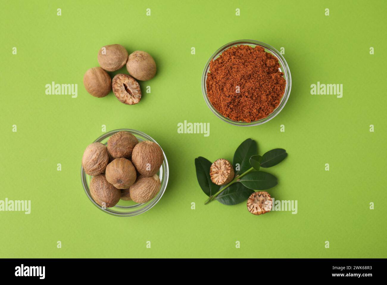 Nutmeg powder, seeds and branch on light green background, flat lay ...