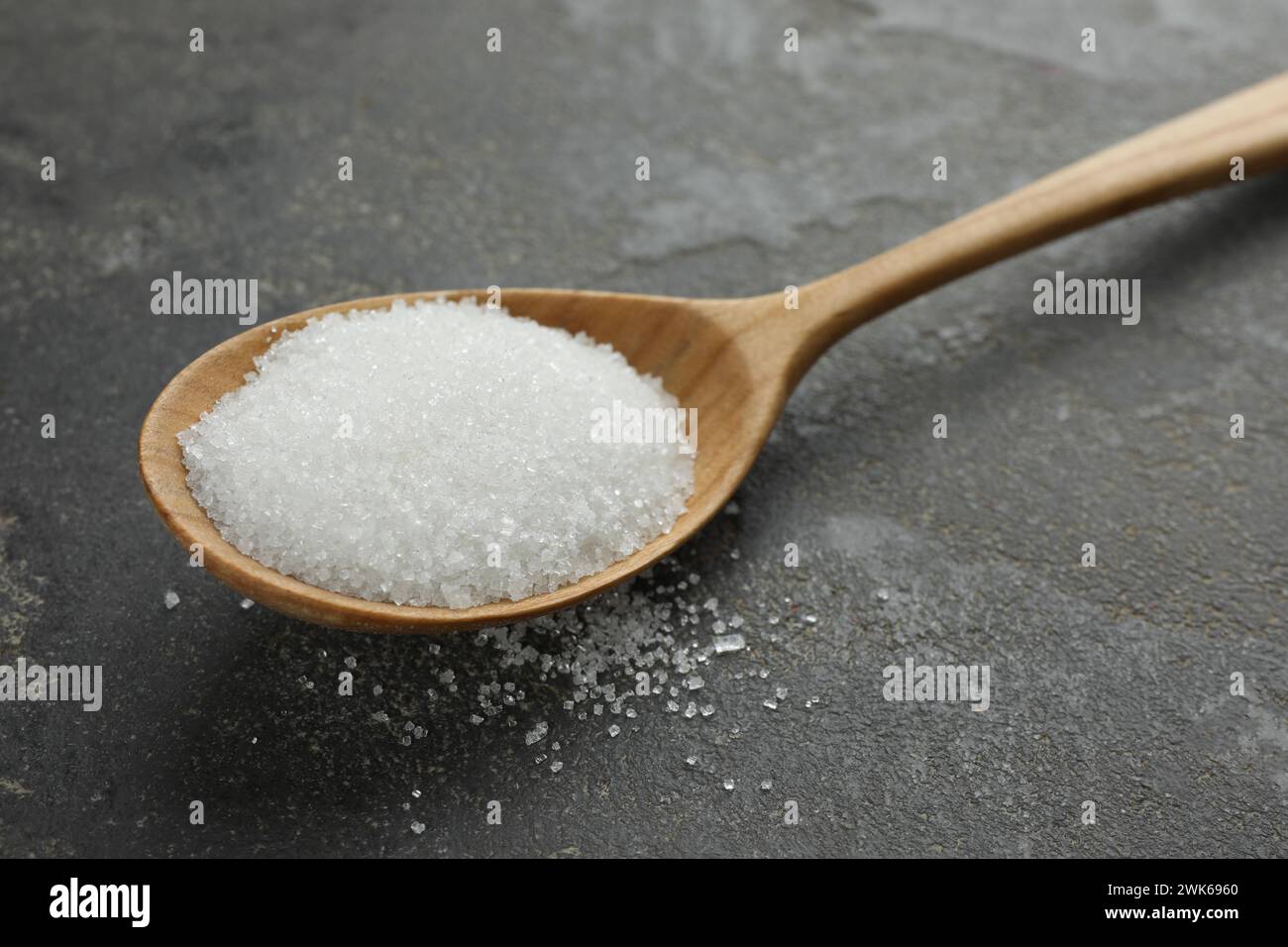 Spoon with granulated sugar on grey textured table, closeup Stock Photo ...