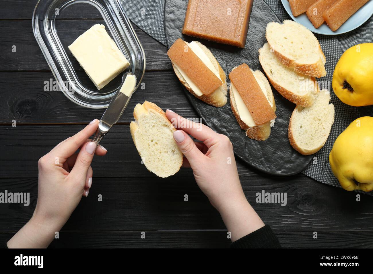 Making sandwich with quince paste. Woman spreading butter on bread at ...
