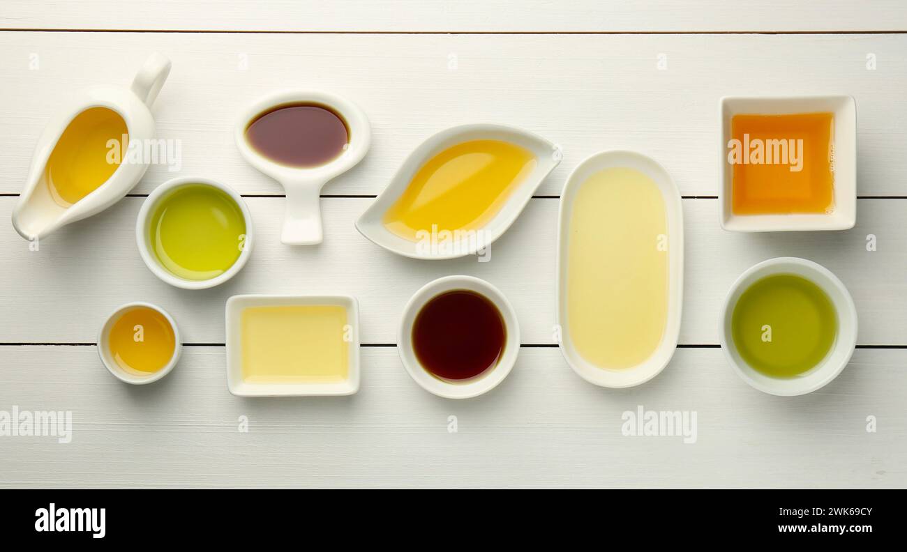 Vegetable fats. Different cooking oils on white wooden table, flat lay ...