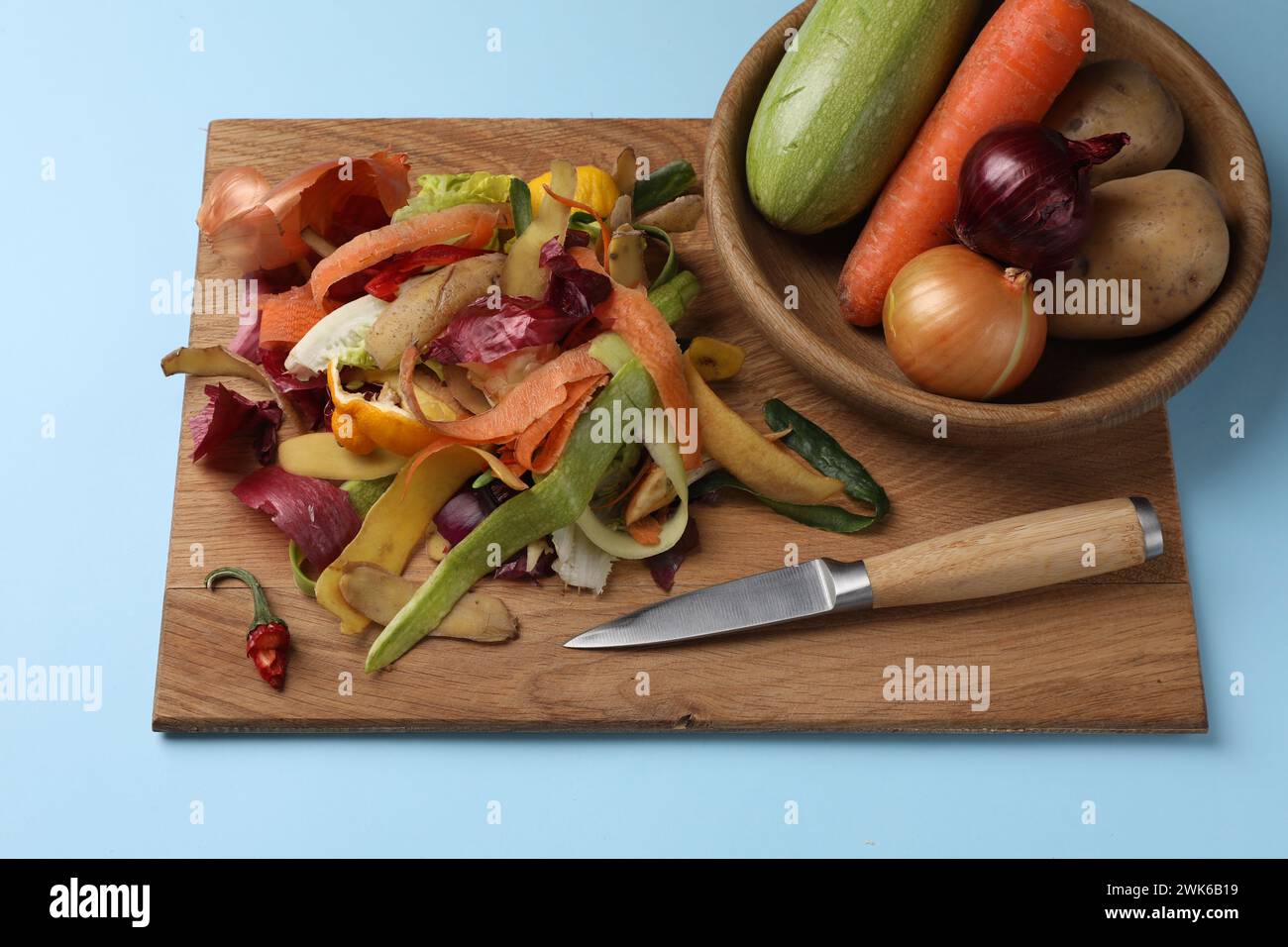 Different fresh vegetables with peels and knife on light blue ...