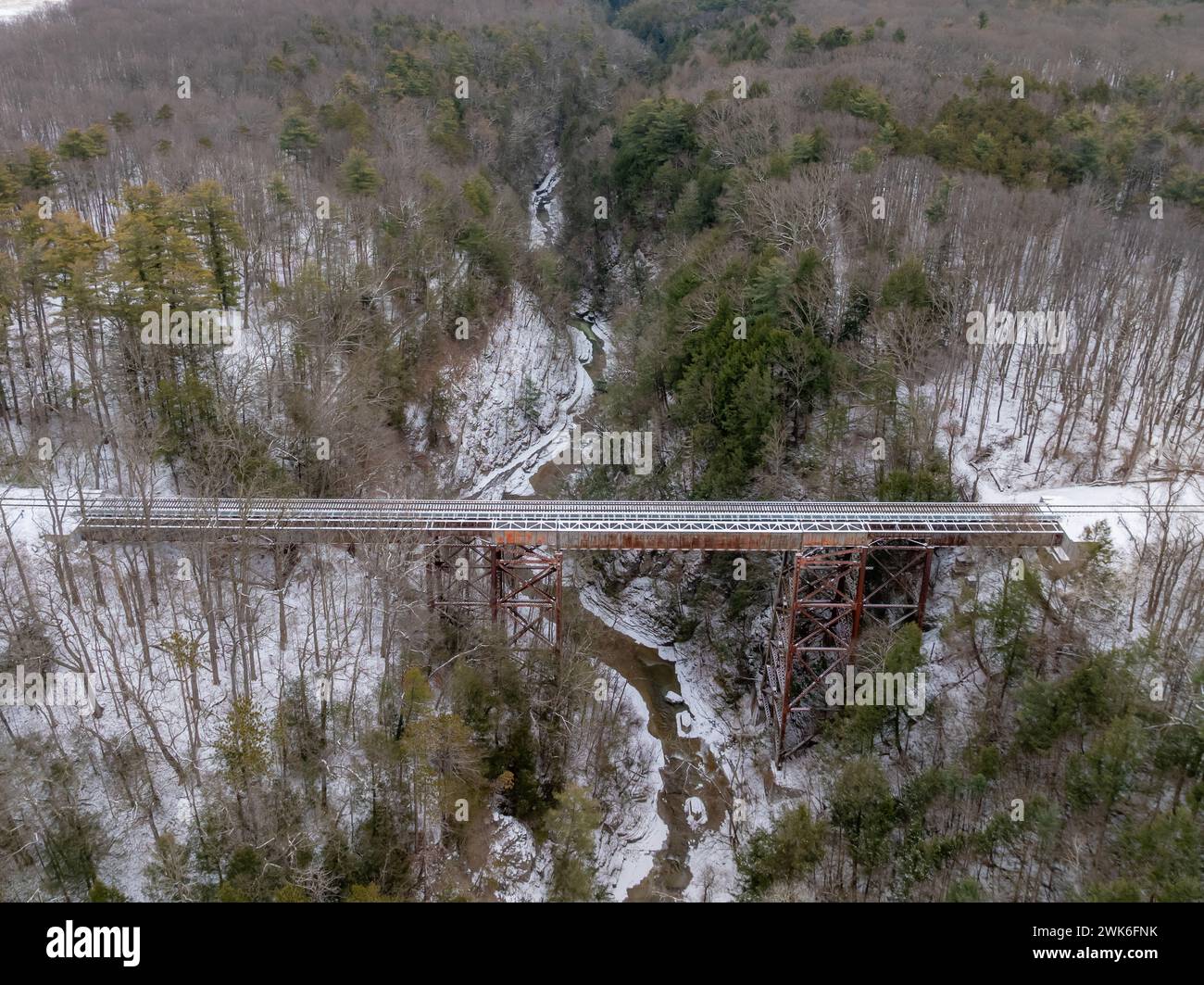 Winter aerial photos of a rusty old iron railway bridge over a forest ...