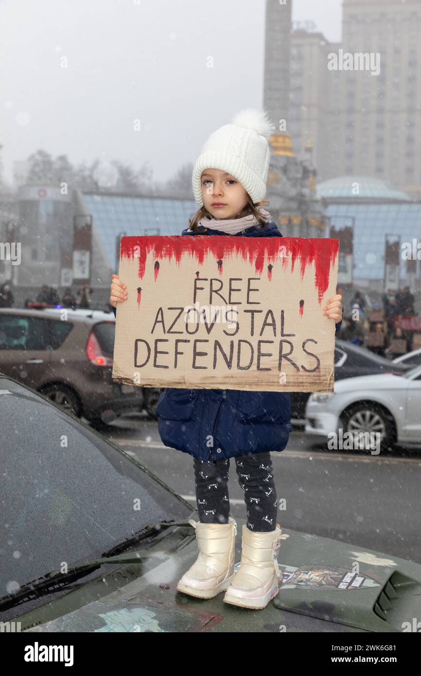 A child is seen standing with a placard that says "Free Azovstal ...