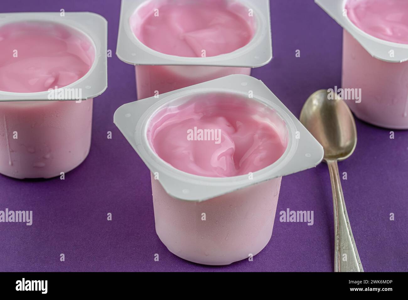 Pink yogurt cup with defocused cups on purple background - kid yogurt ...
