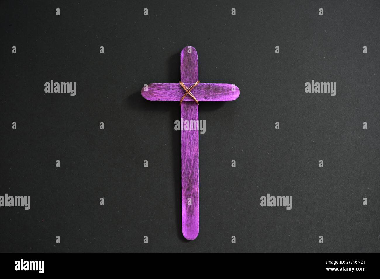 A purple wooden cross in black background. Christian faith, holy week ...