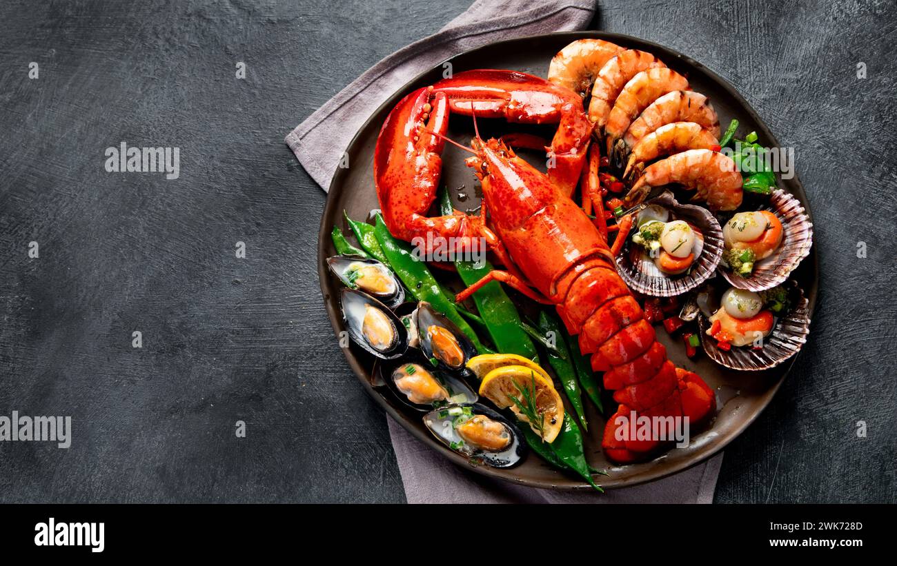 Big red lobster on plate with shrimp and mussels with lemon, souce ...