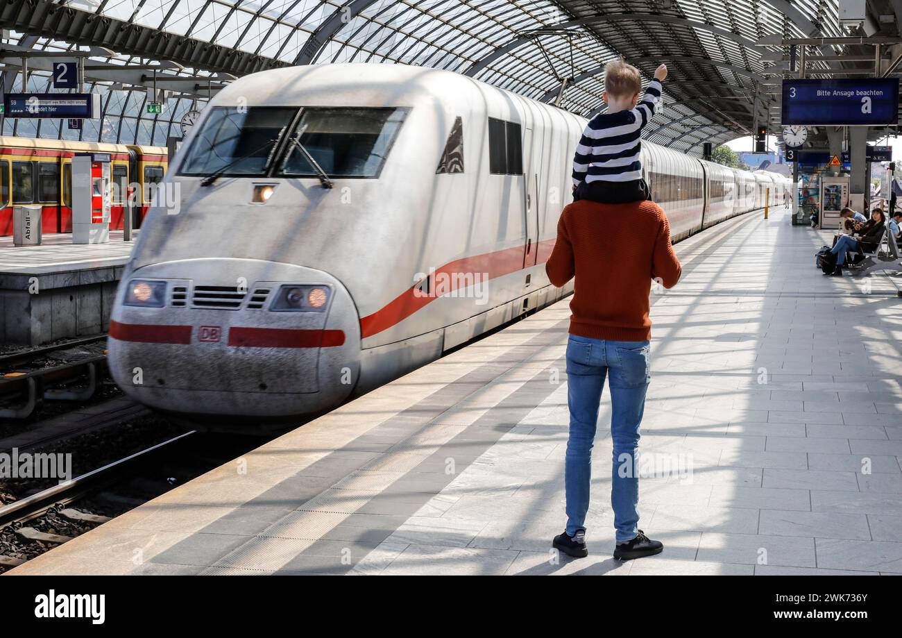 A father carries his son on his shoulder while a Deutsche Bahn ICE ...
