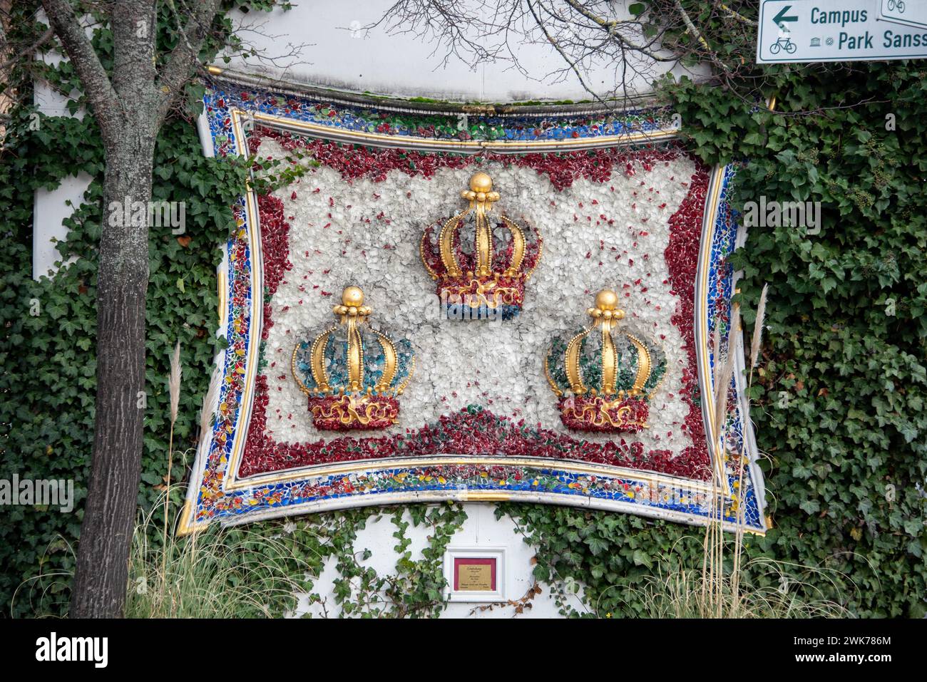 Wall mosaic with crown motifs on an exterior wall with trees in the ...