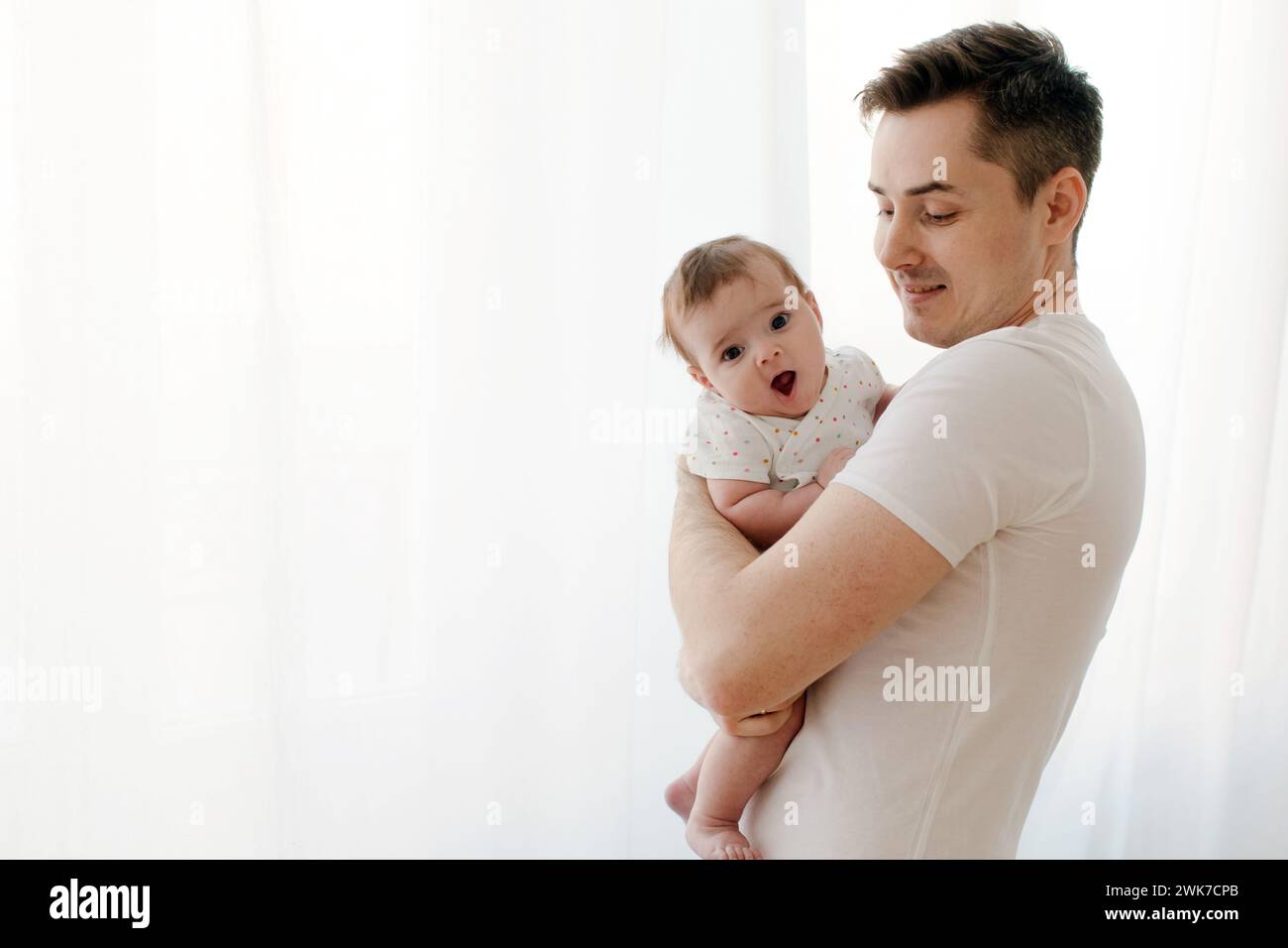 Happy father with baby in arms at home Stock Photo - Alamy
