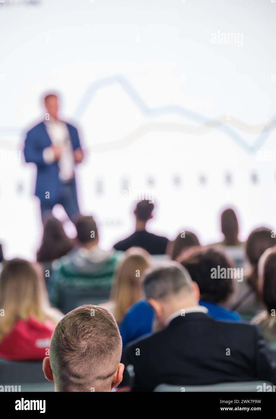 Blurred view of a business speaker presenting to an audience with focus ...