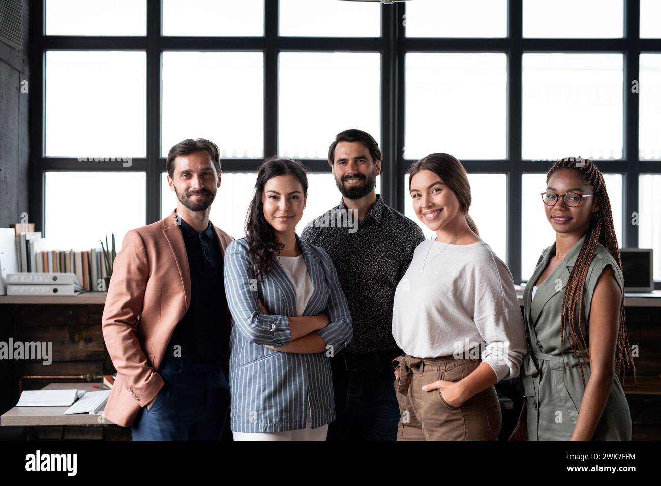 Group of colleagues standing in modern office, looking at camera ...