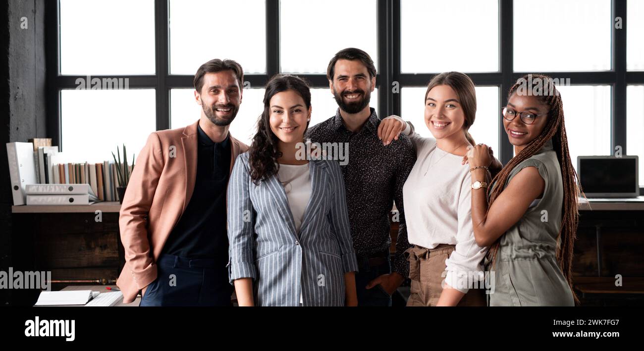 Group of colleagues standing in modern office, looking at camera ...