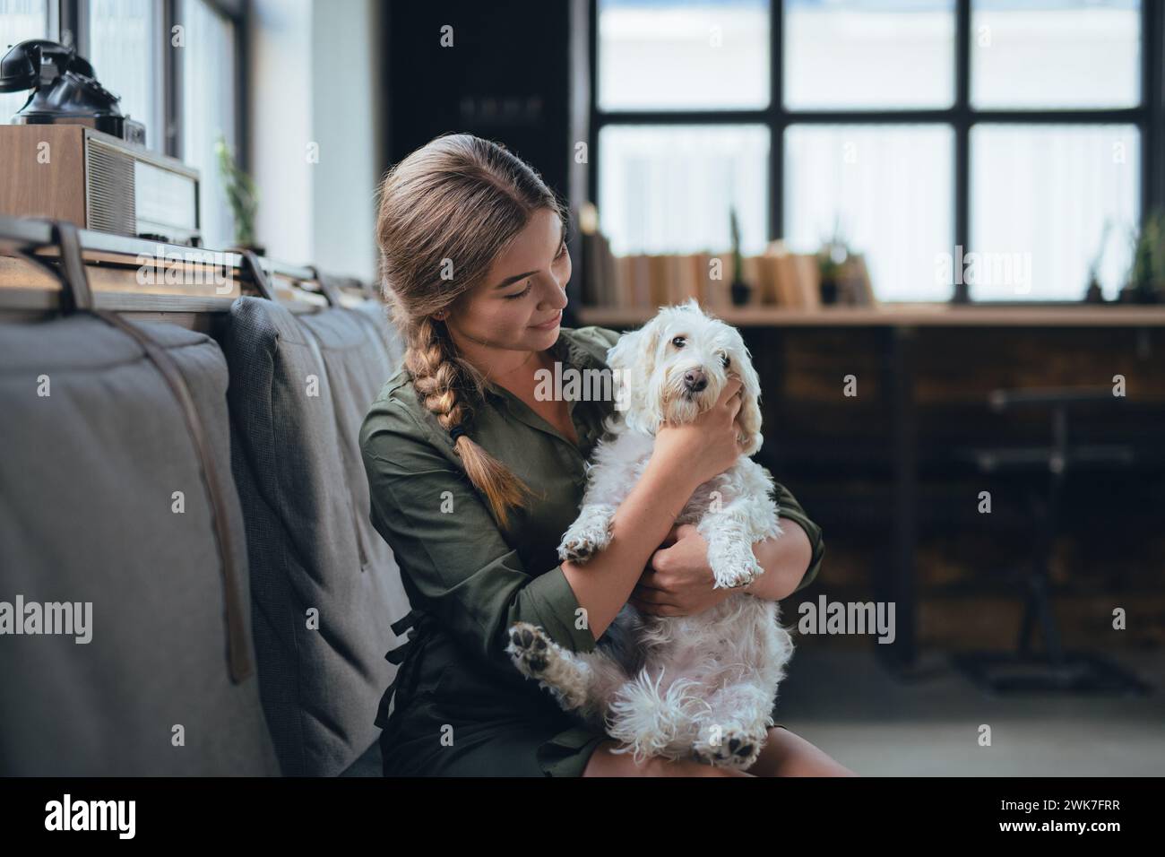 Portrait of beautiful young woman holding her dog in hands. Cute white ...