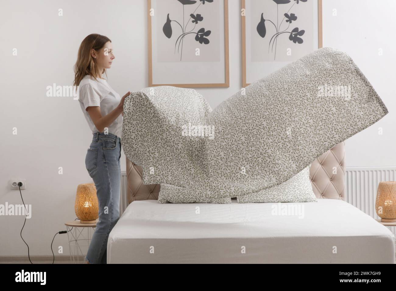 Woman changing bed linens at home in her bedroom, cozy domestic ...