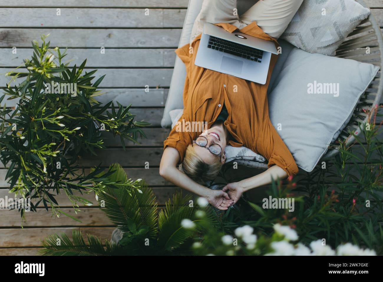 Top view of woman working outdoors in the garden, with laptop on legs ...