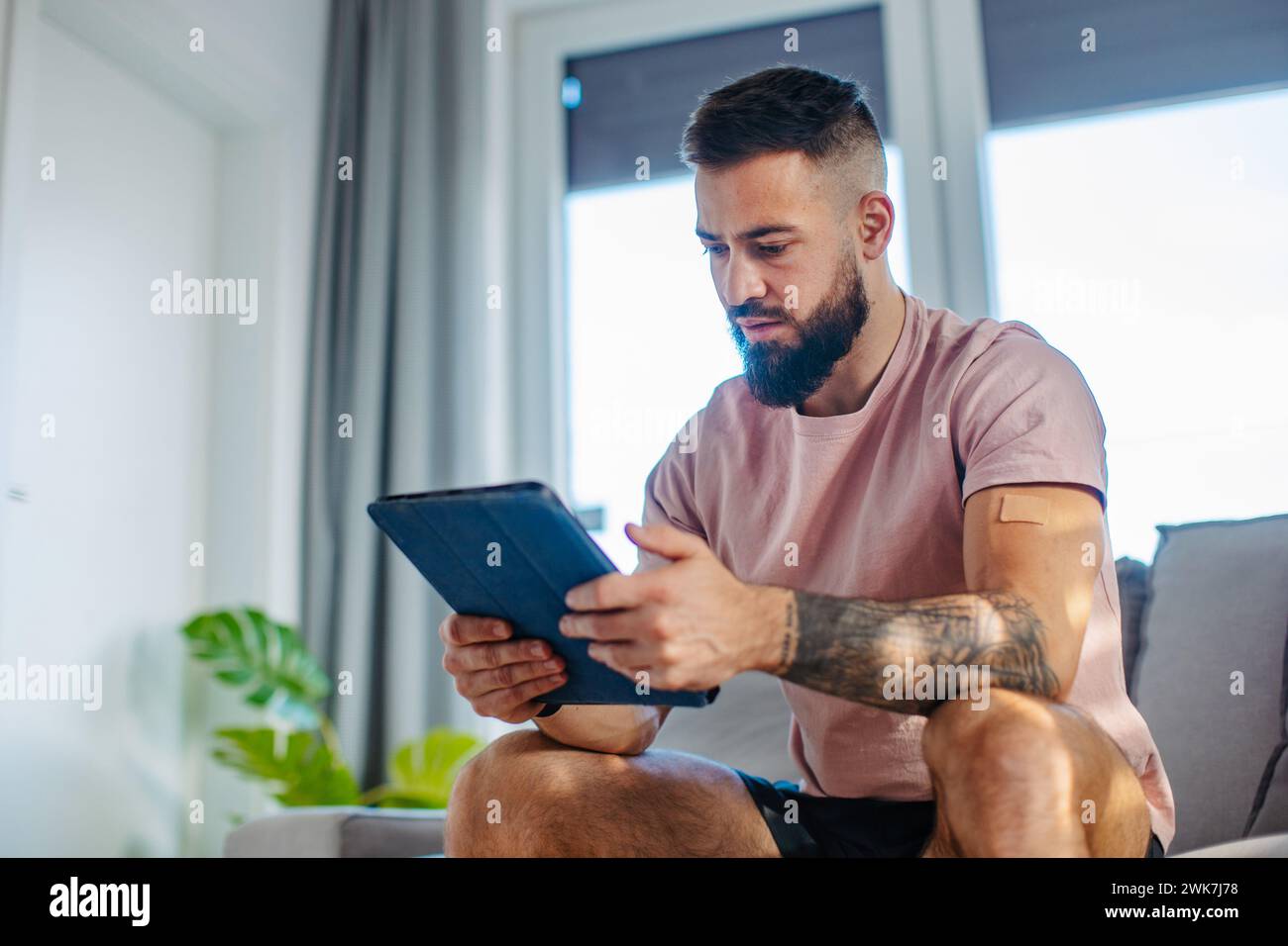 Young man with nicotine patch on his shoulder, holding tablet. New Year ...