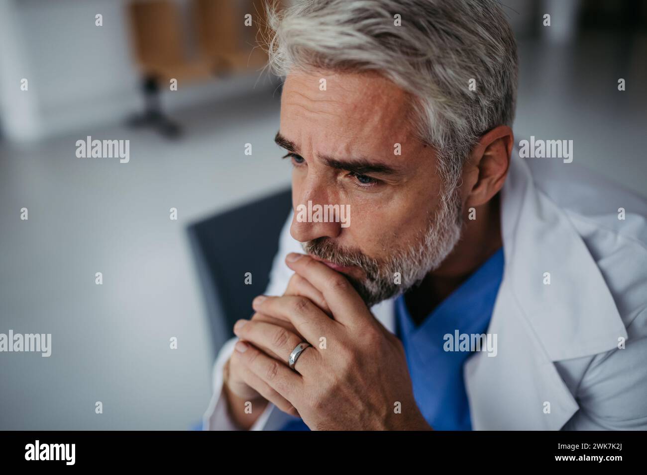 Side view of frustrated, exhausted doctor sitting in hospital corridor ...