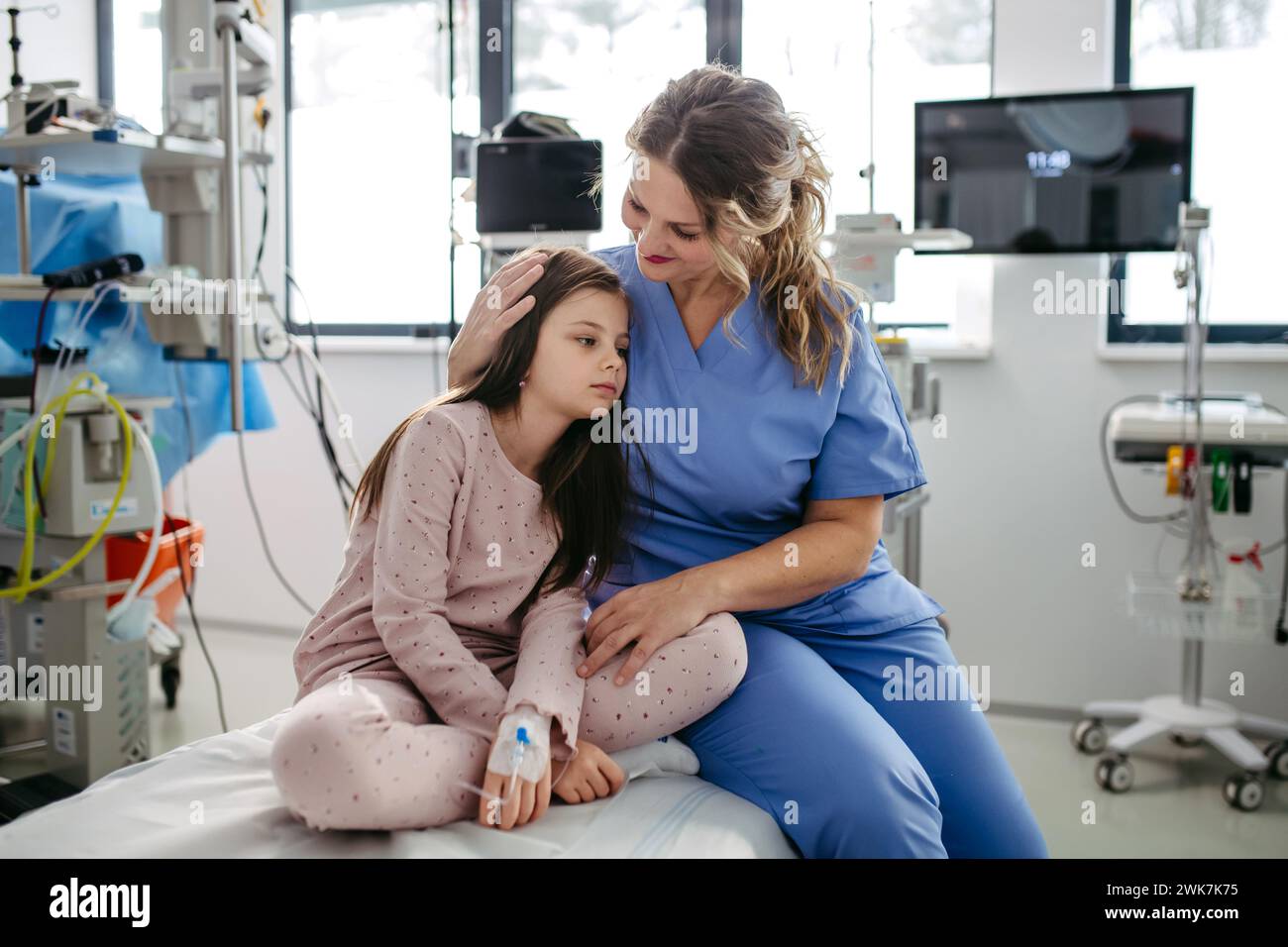 Supportive doctor soothing a worried children patient in emergency room ...