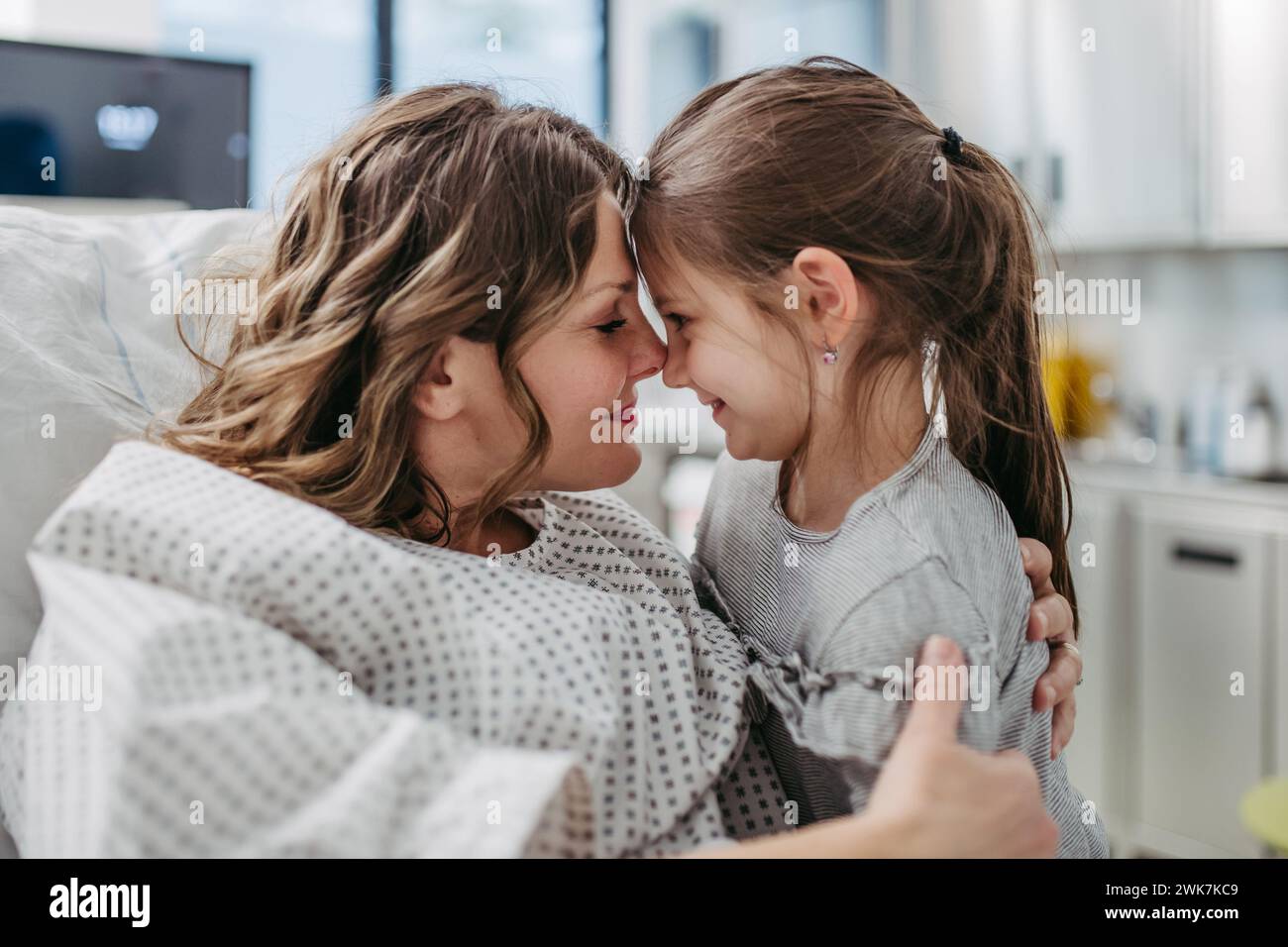 Daughter visiting mother in hospital after successful surgery, hugging ...