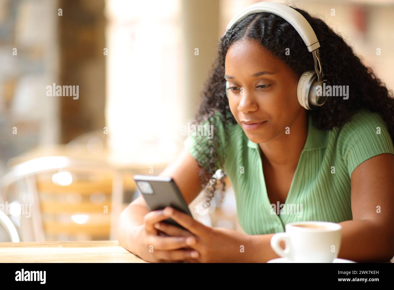 Black woman wearing headphone listening to music using phone and ...