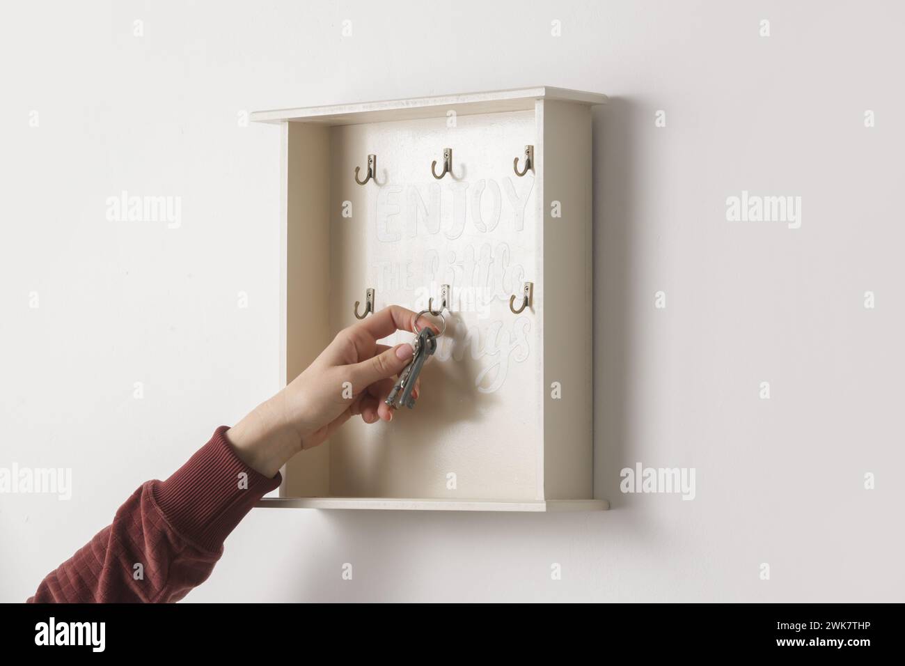 Young woman is hanging keys on the key holder on the wall, domestic ...