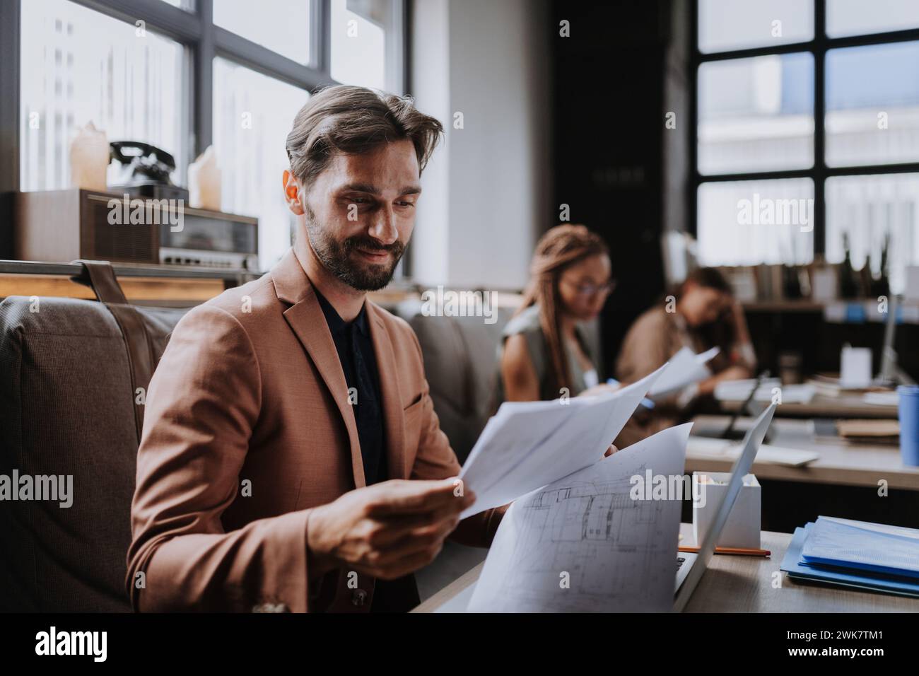Businessman working on laptop, reading documents in modern office or ...
