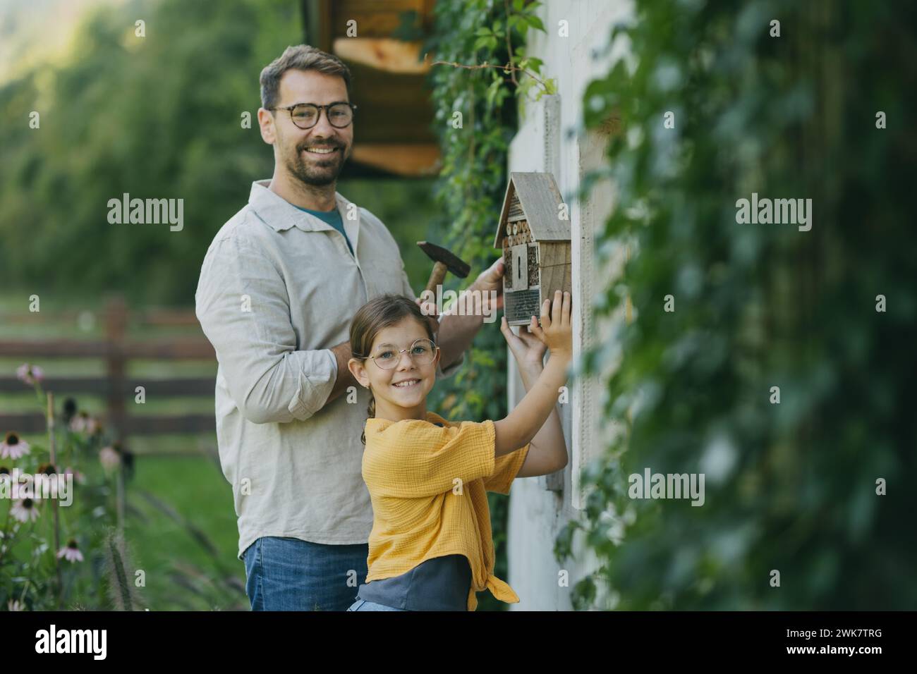 Father with daughter making bug hotel, or insect house outdoors in the ...