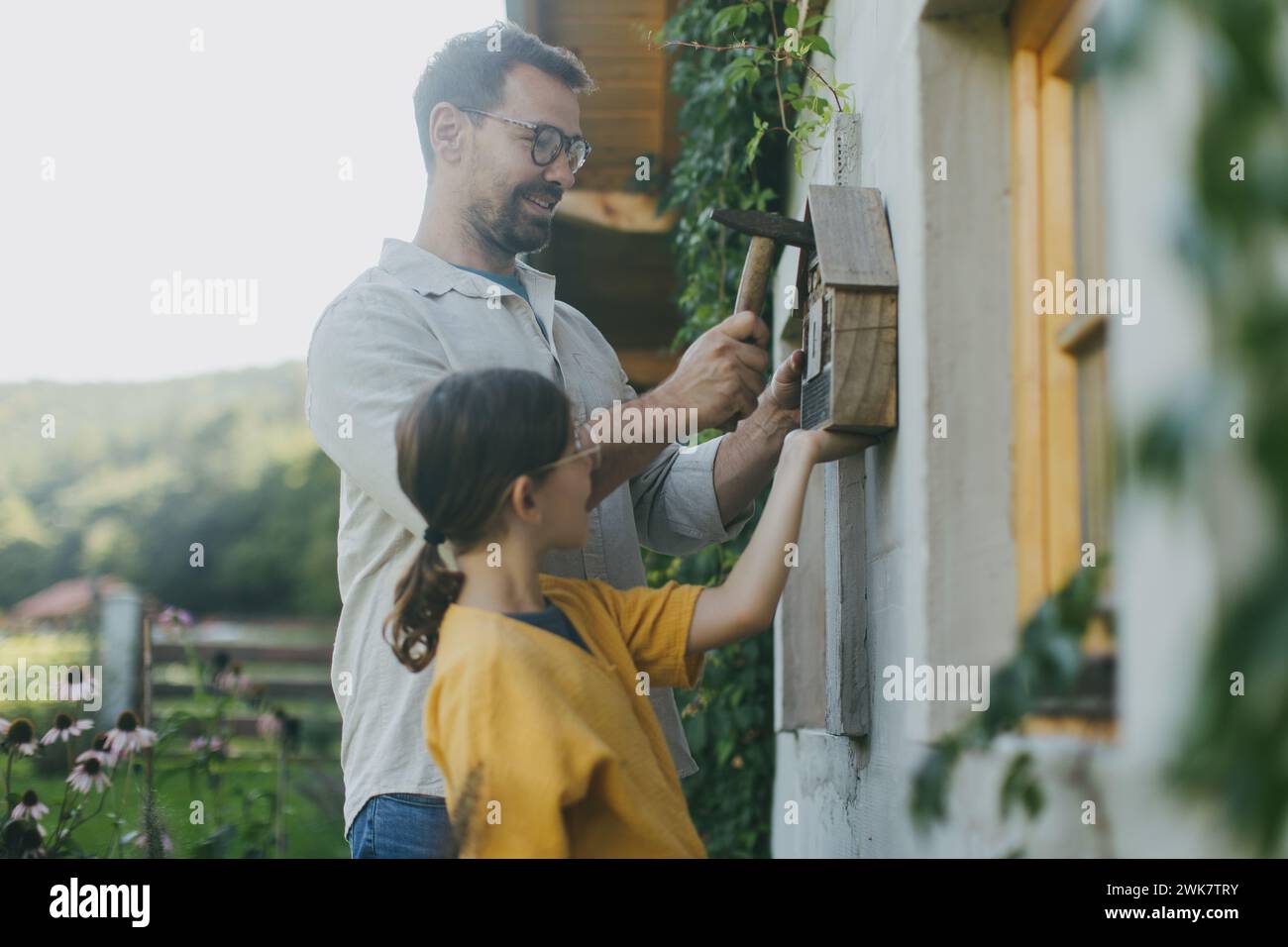 Father with daughter making bug hotel, or insect house outdoors in the ...
