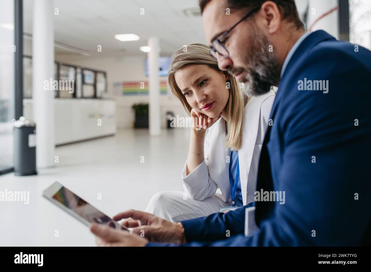 Pharmaceutical sales representative talking with doctor in clinic lobby ...