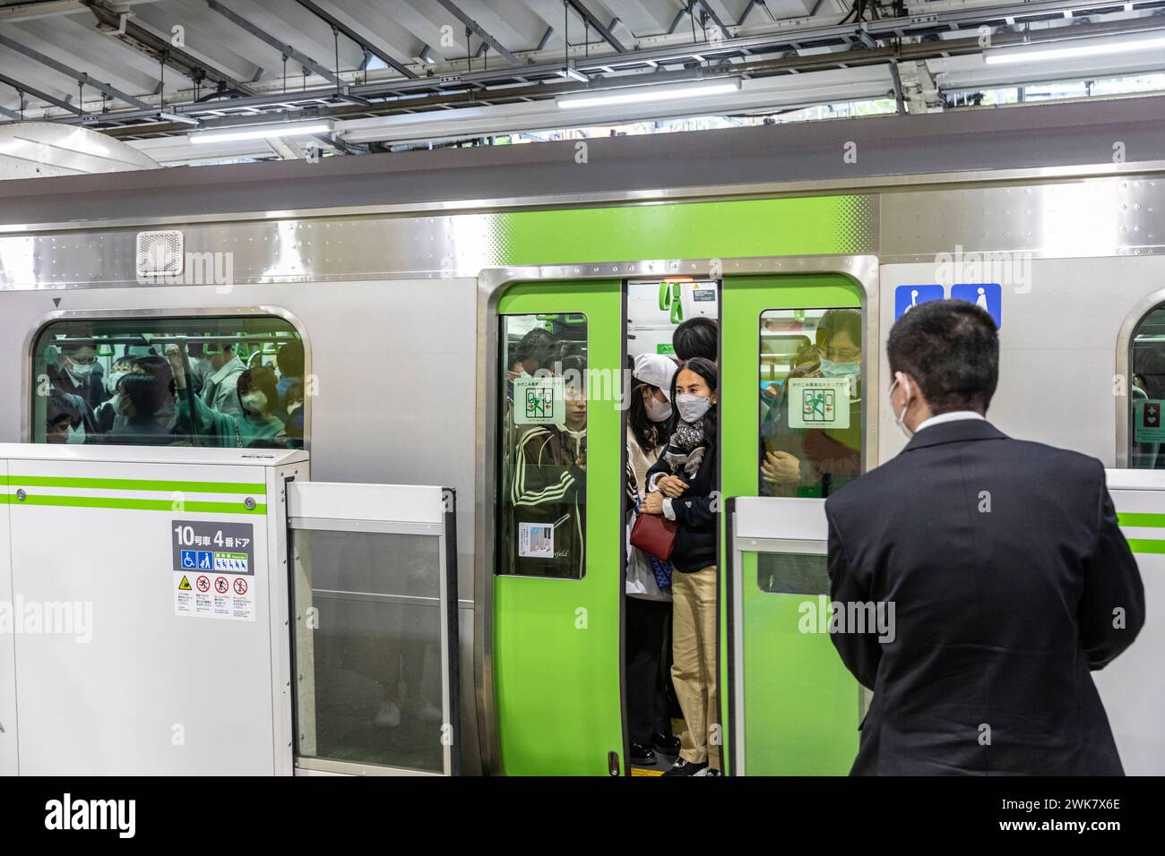 Crowded train Tokyo Japan, carriage doors open and barrier slides back ...
