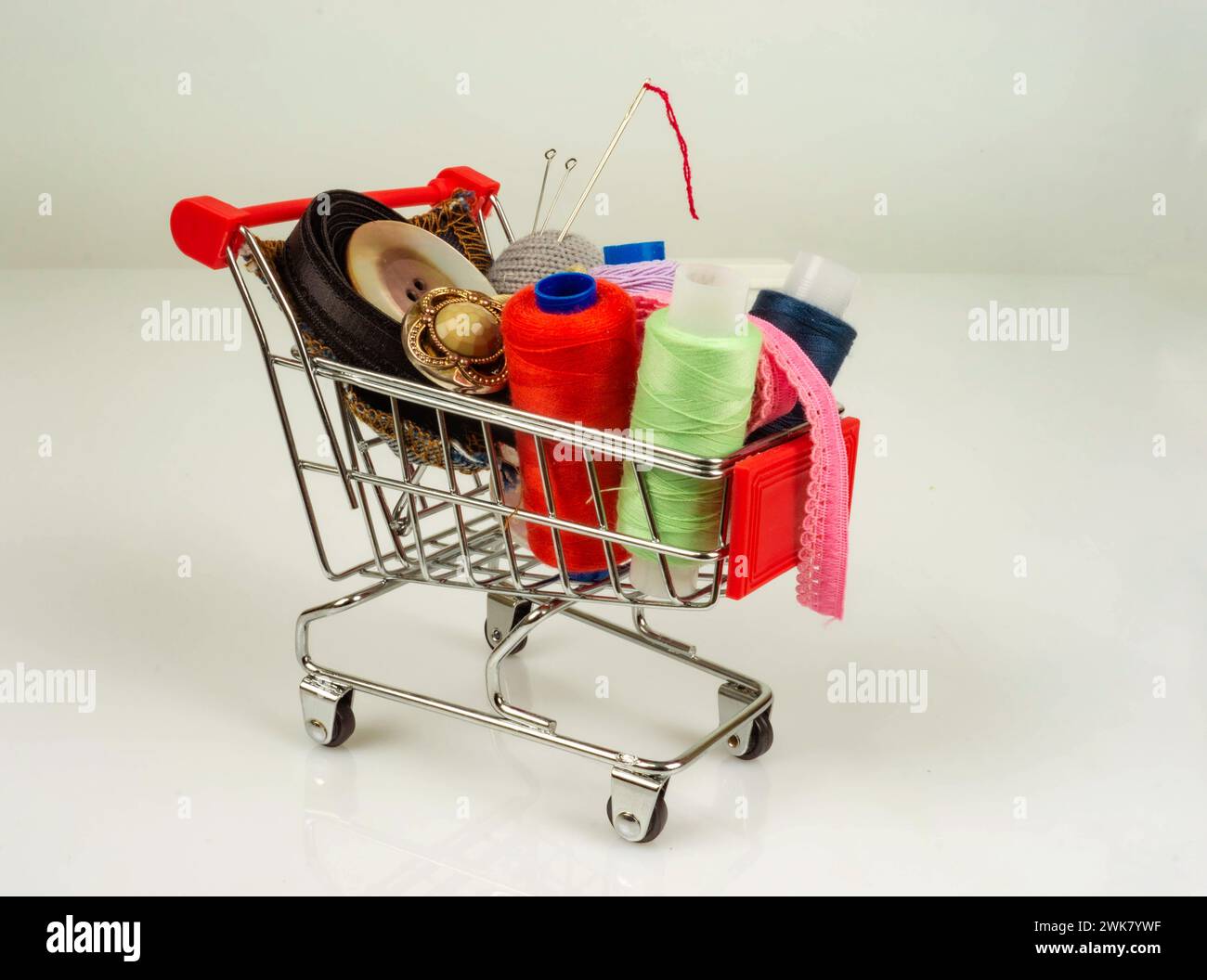 A shop cart with threads, sewing accessories and buttons. White ...