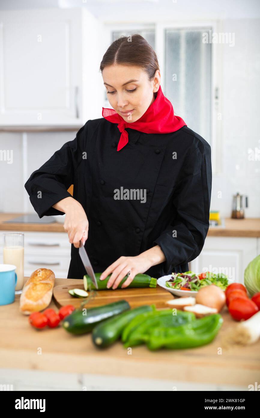 Female cook in black uniform chopping vegetables in kitchen Stock Photo ...