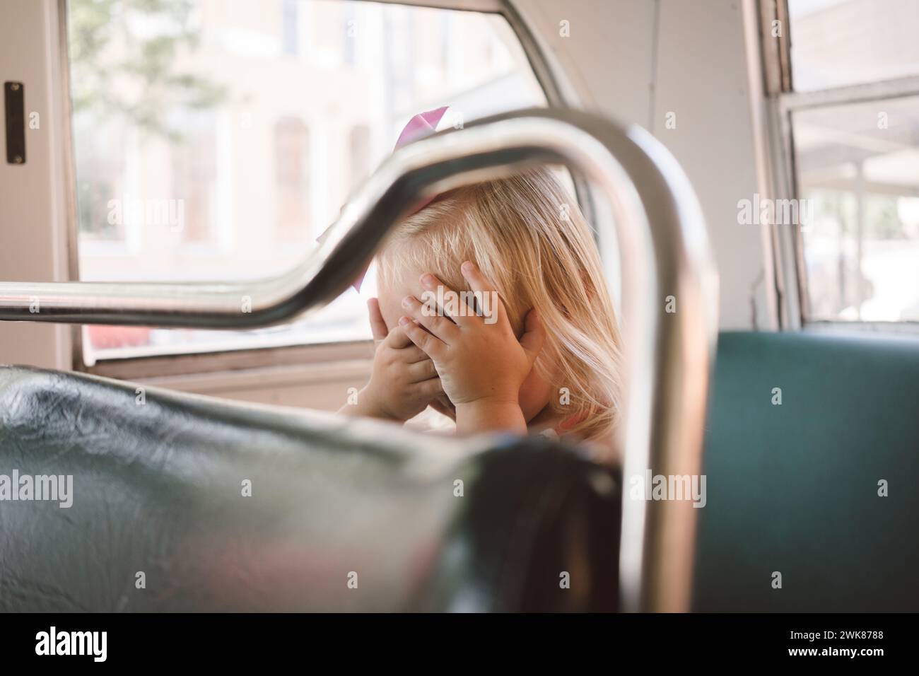 Young girl covers face with hands while sitting on bus seat Stock Photo ...