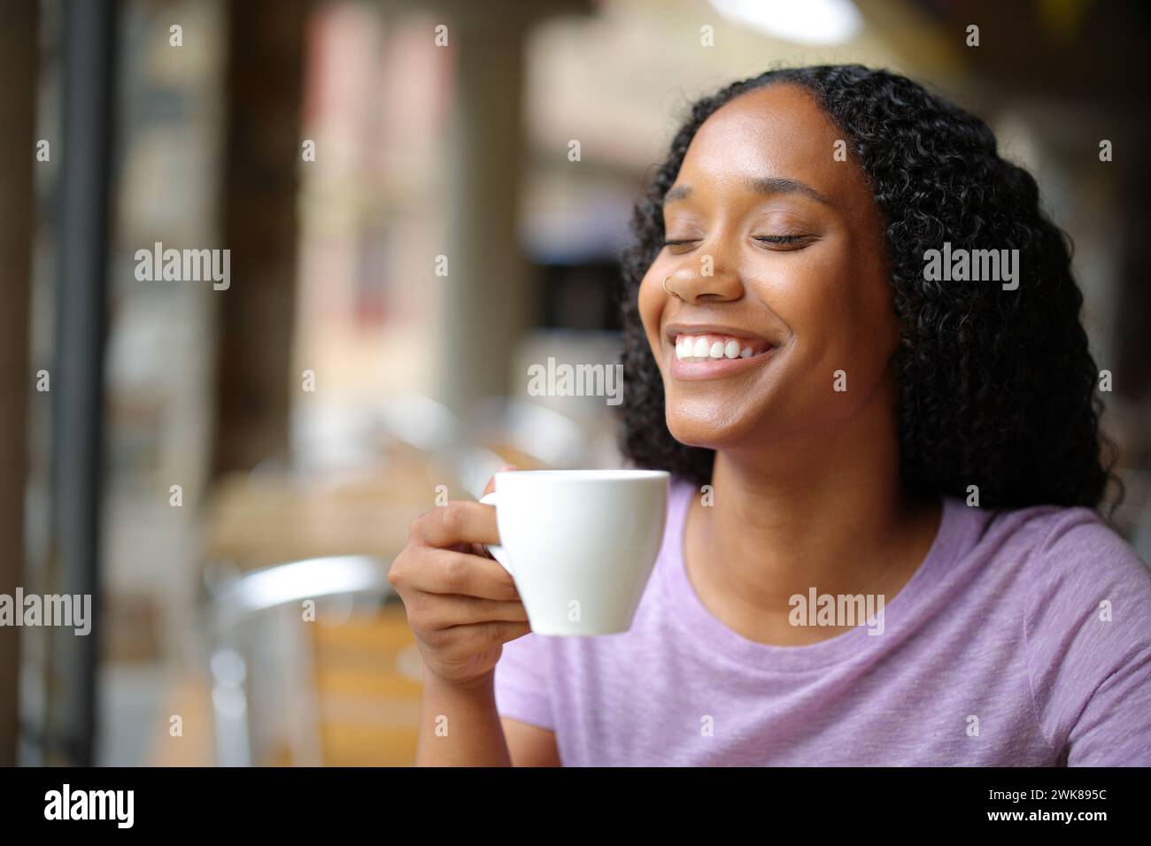 Happy black woman enjoying coffee smiling in a bar terrace Stock Photo ...
