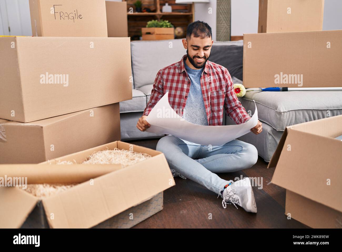 Young hispanic man architect smiling confident reading house plans at ...