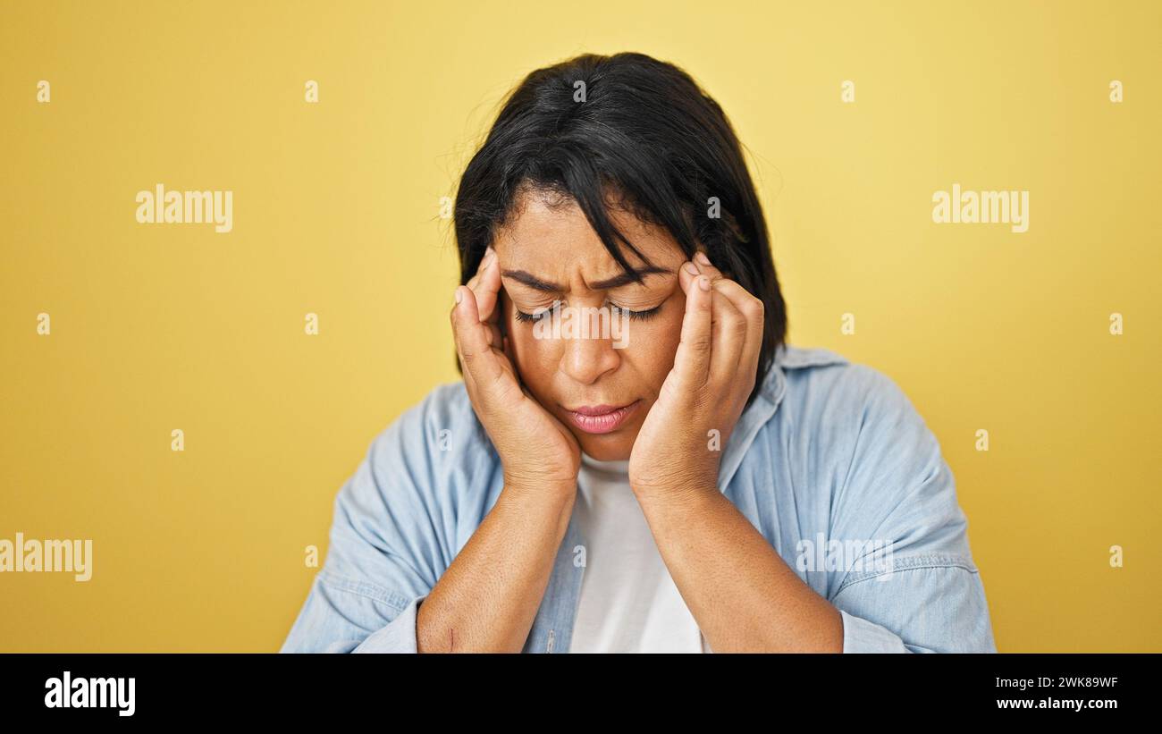A distressed middle-aged hispanic woman stands isolated against a ...