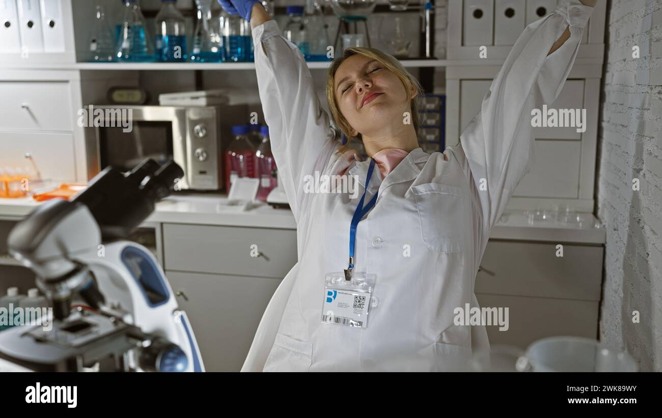 Stressed female scientist stretching in a laboratory with microscope ...