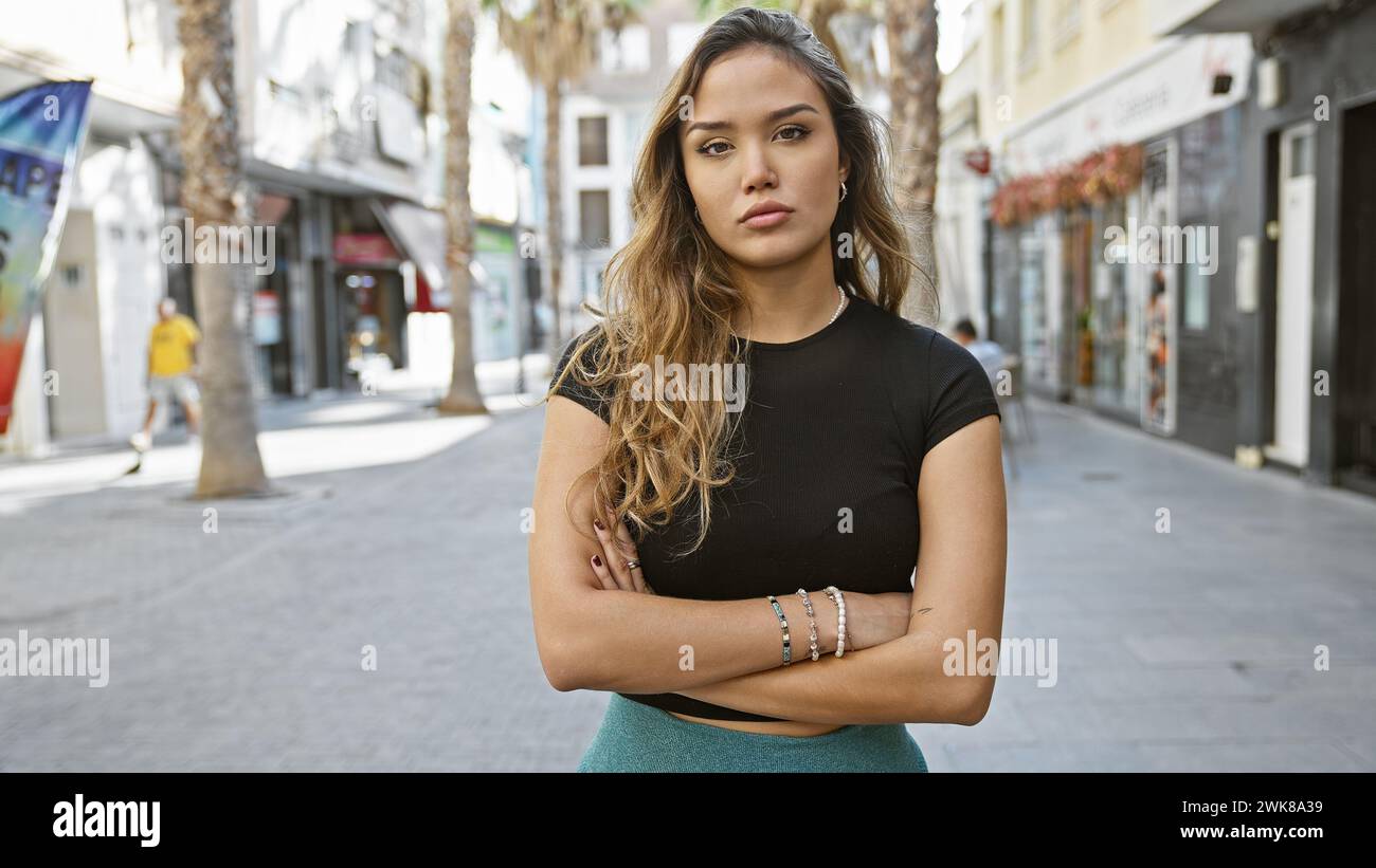 On a sunny city street, a young, beautiful hispanic woman stands ...