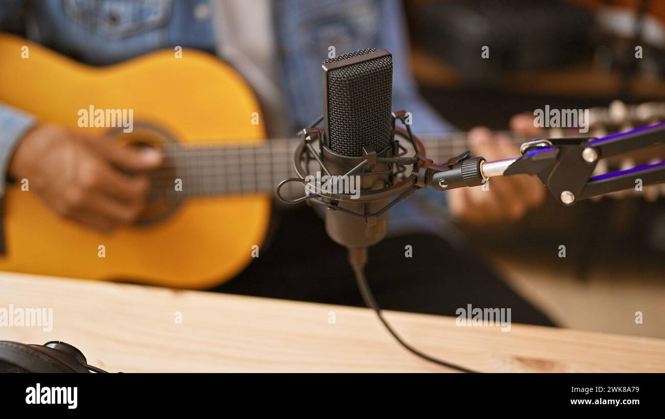 A man plays an acoustic guitar while singing into a microphone in a ...