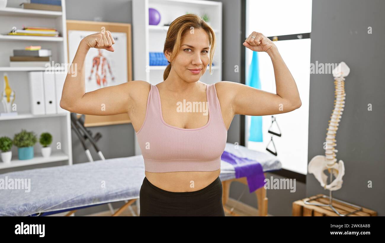 Confident hispanic woman flexing muscles in rehabilitation center ...
