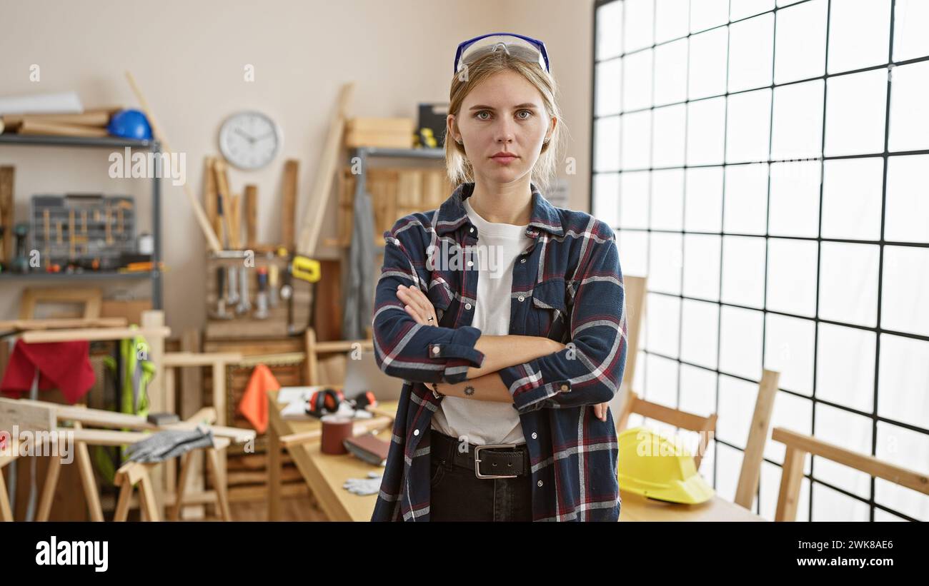 A confident blonde woman with blue eyes stands cross-armed in a well ...