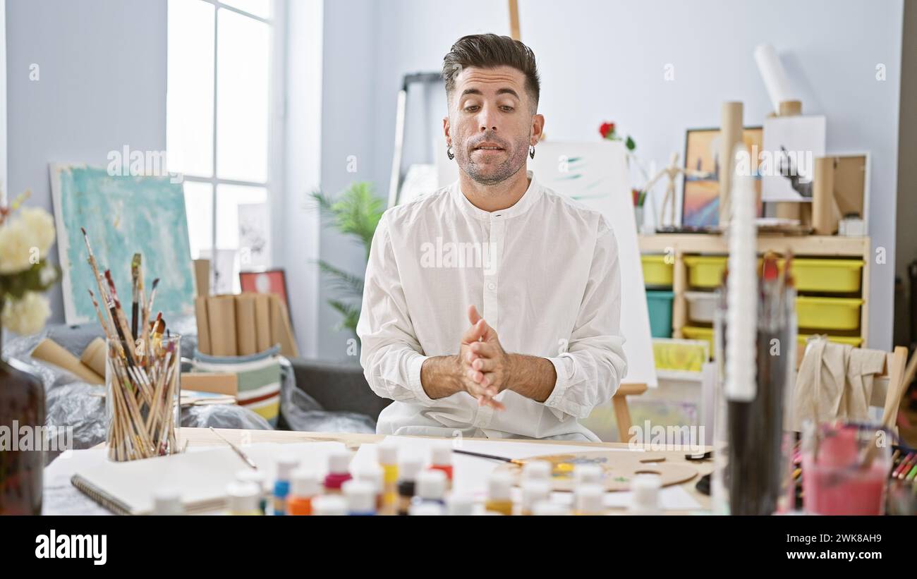 Young, handsome hispanic man ardently drawing on paper, deeply ...