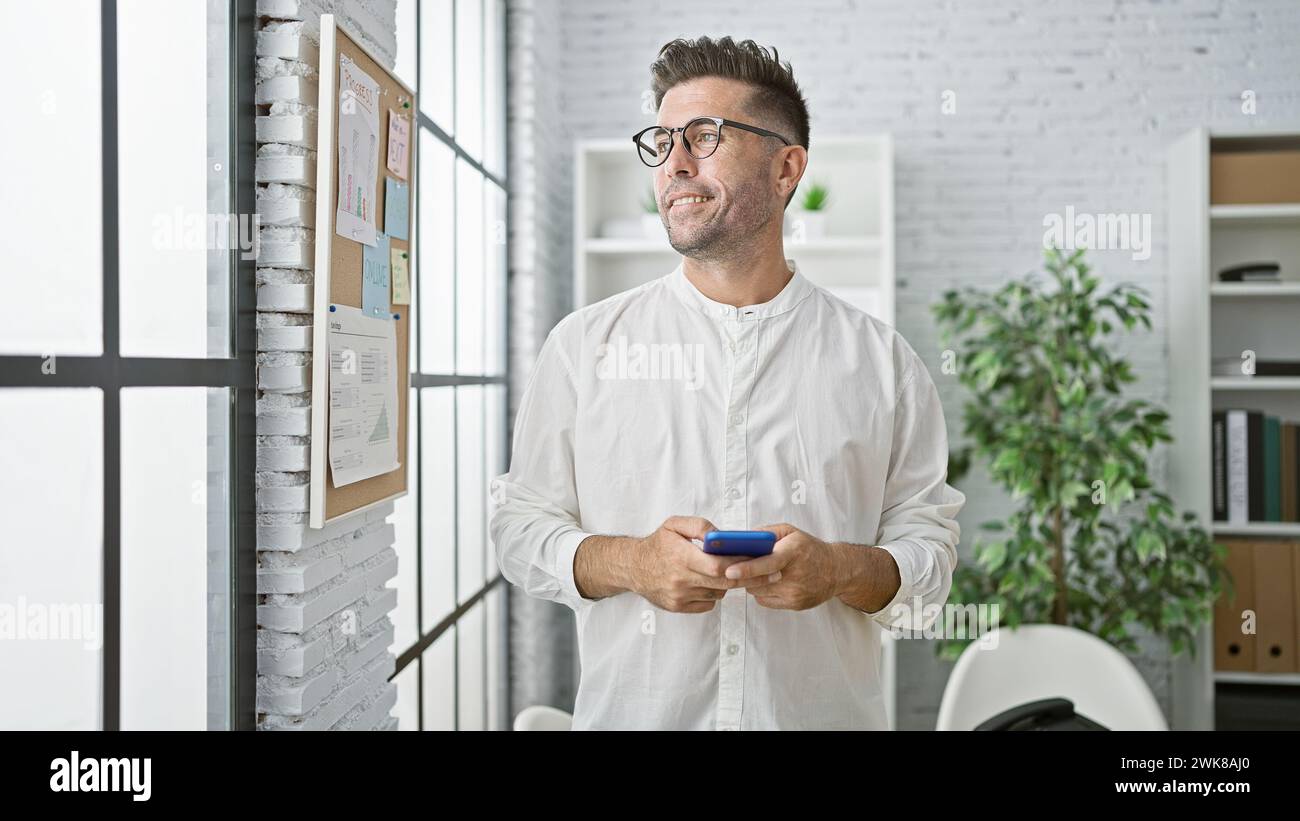 Confident young hispanic man smiling, working in the office, focused on ...
