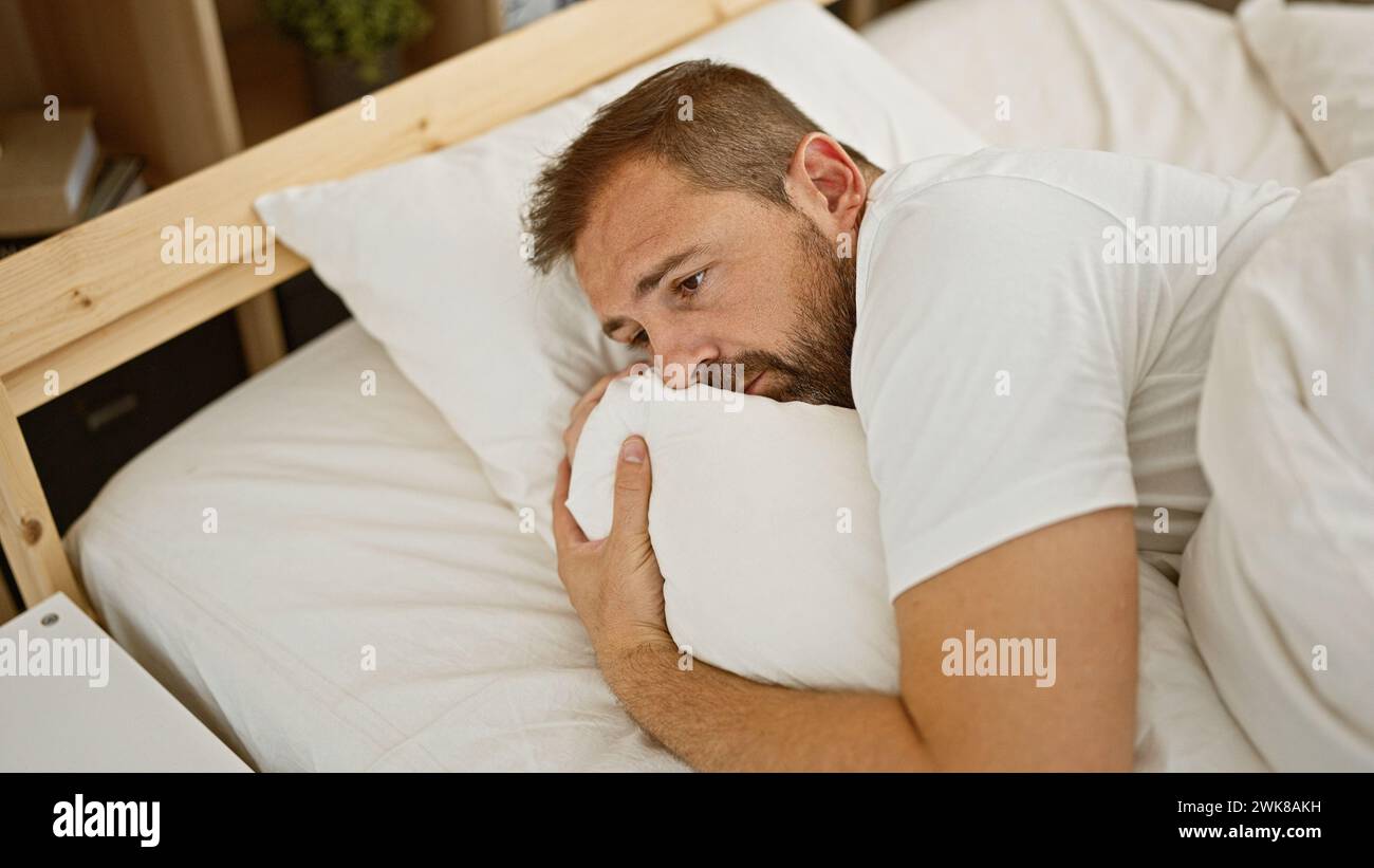 Worried middle-aged man with grey hair lying in bed indoors, portraying ...