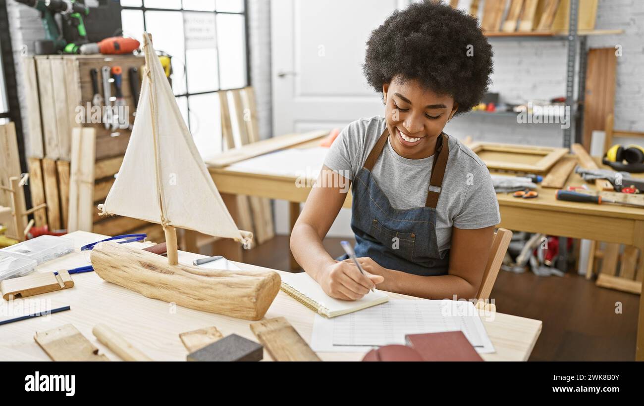 A smiling african american woman carpenter writing in a notebook in a ...