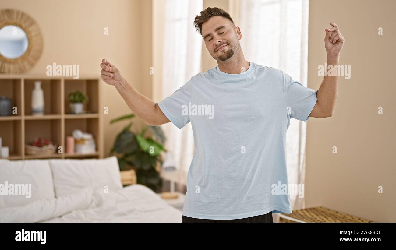Relaxed young hispanic man stretching in a bright cozy bedroom Stock ...