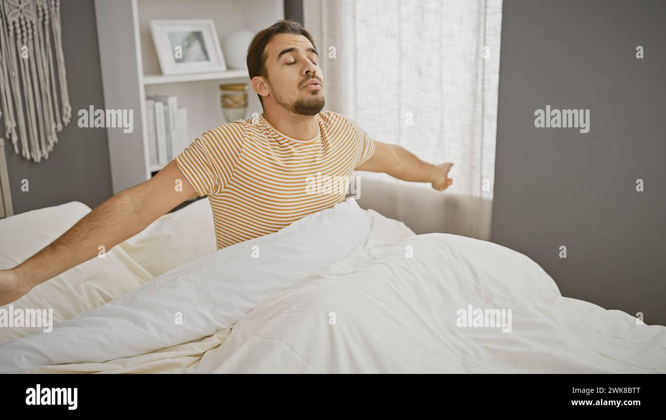 Hispanic young man stretching in a cozy modern bedroom upon waking ...
